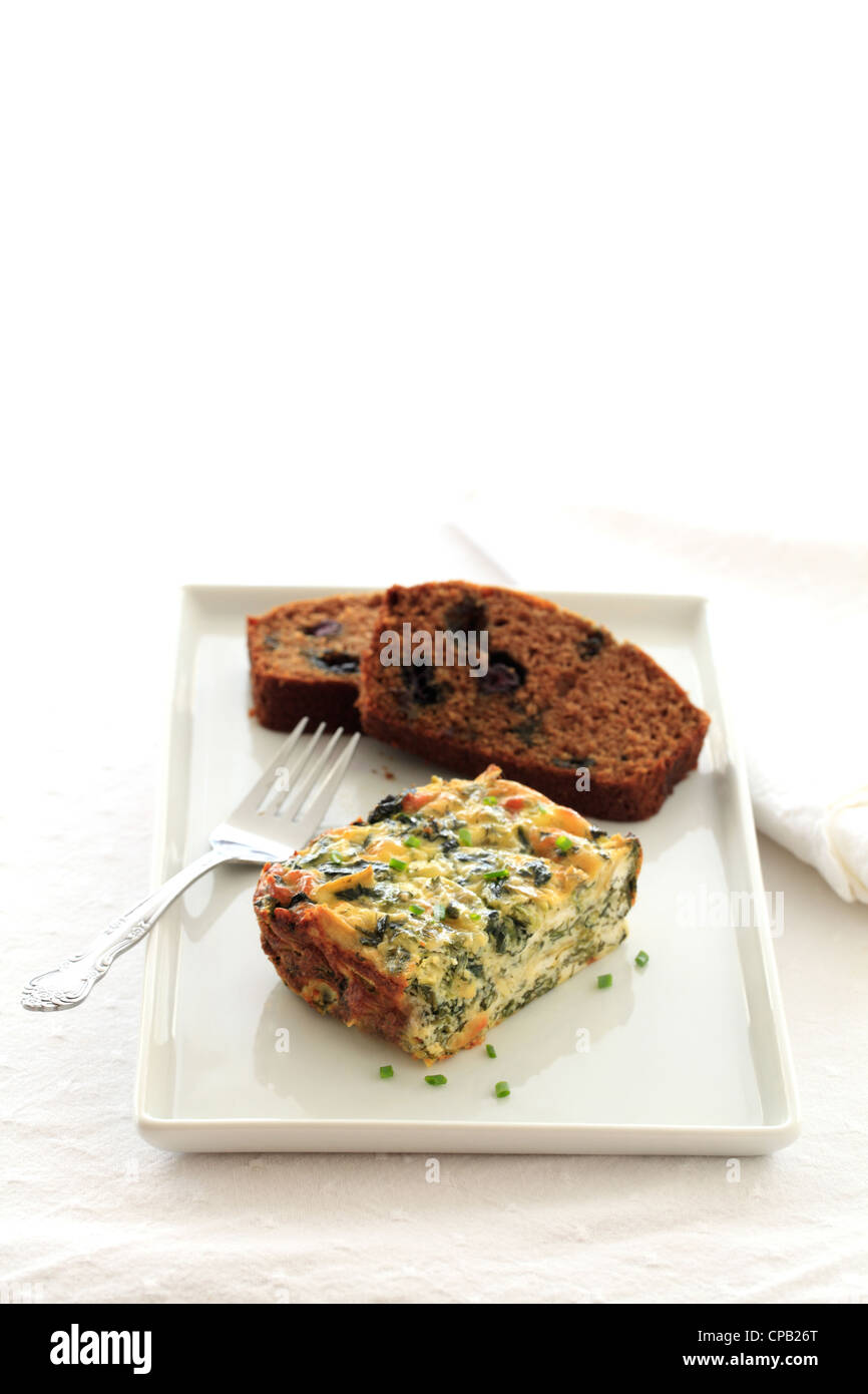 A Spinach frittata served with bread containing fresh fruit Stock Photo ...