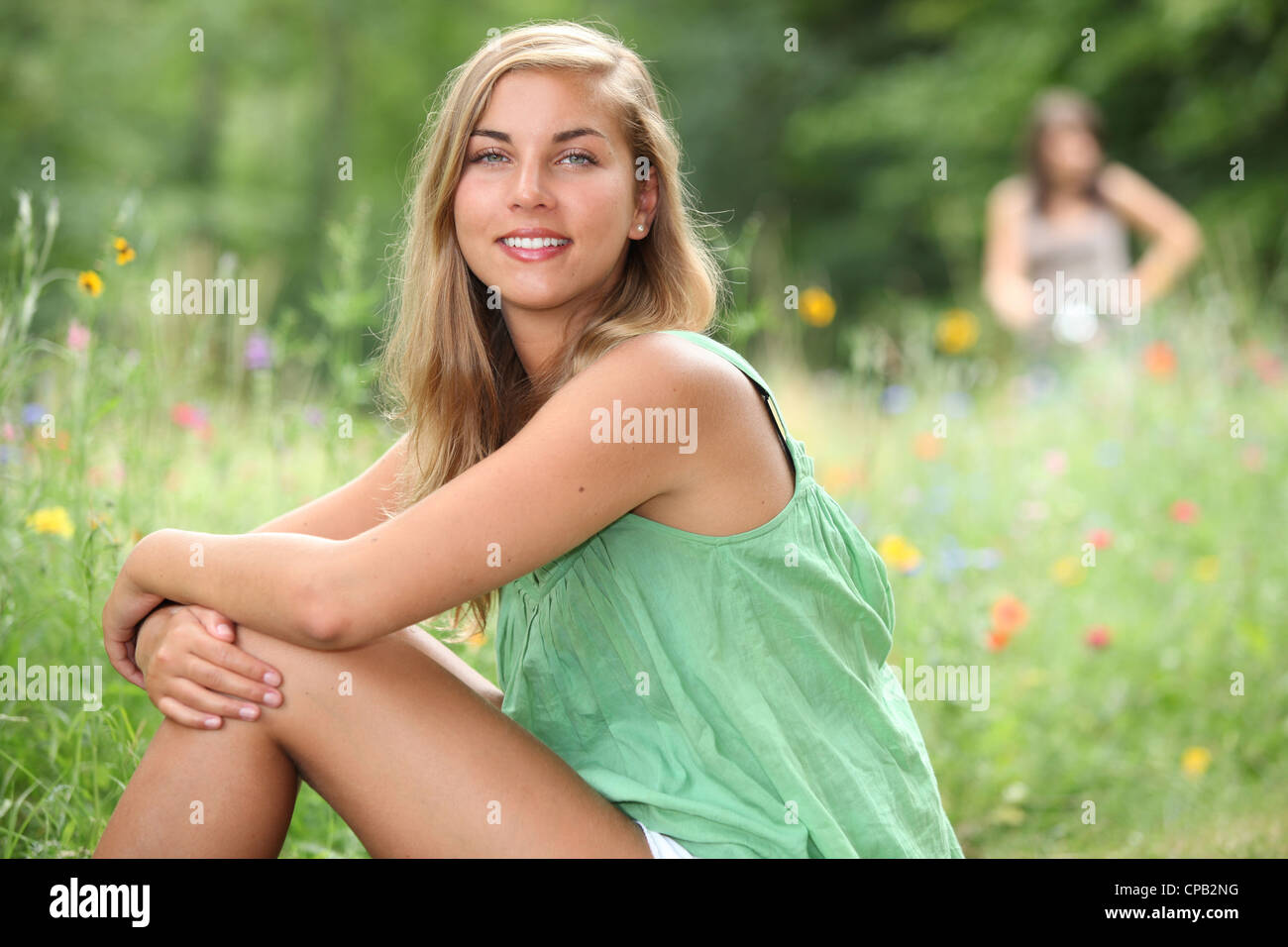 Two female teenagers sat in field Stock Photo - Alamy