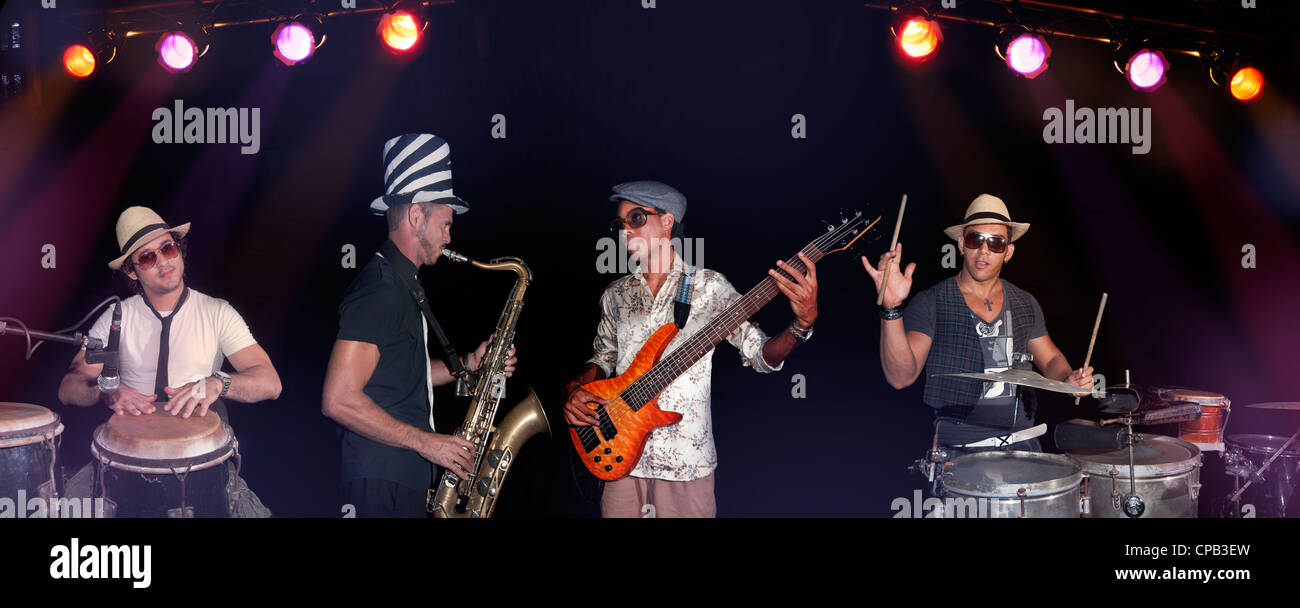 Portrait of four musicians playing on stage against black background ...