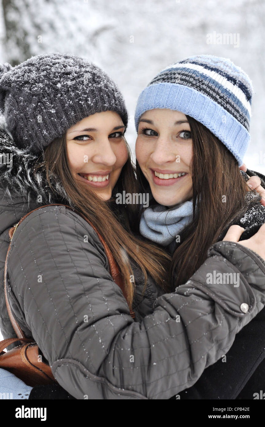 Two young girl wearing warm winter clothes in winter park Stock Photo ...