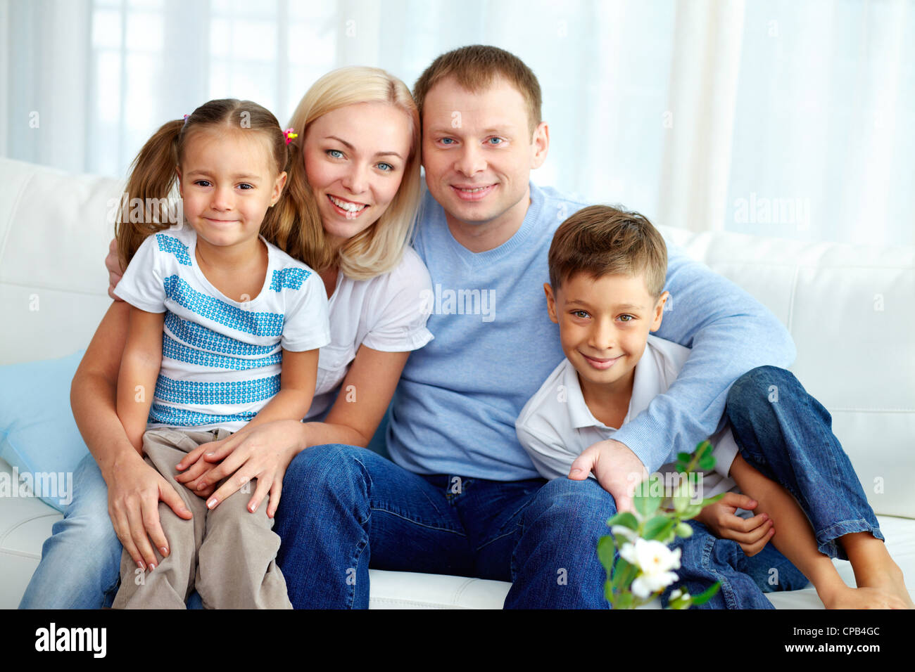 Portrait of happy family with two children sitting at home Stock Photo ...