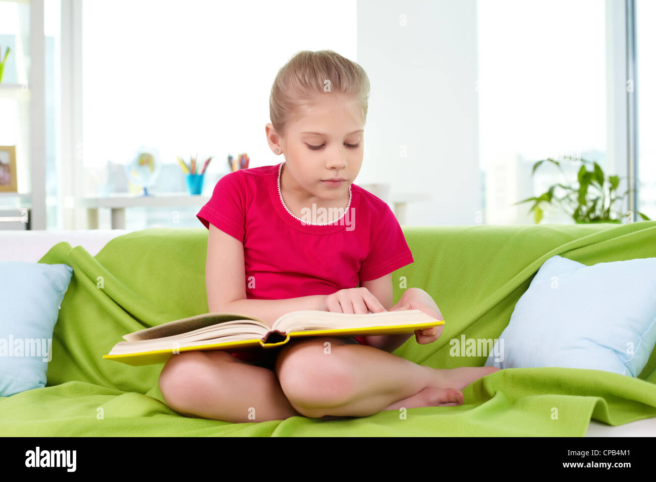 Portrait of lovely girl reading big book at home Stock Photo - Alamy