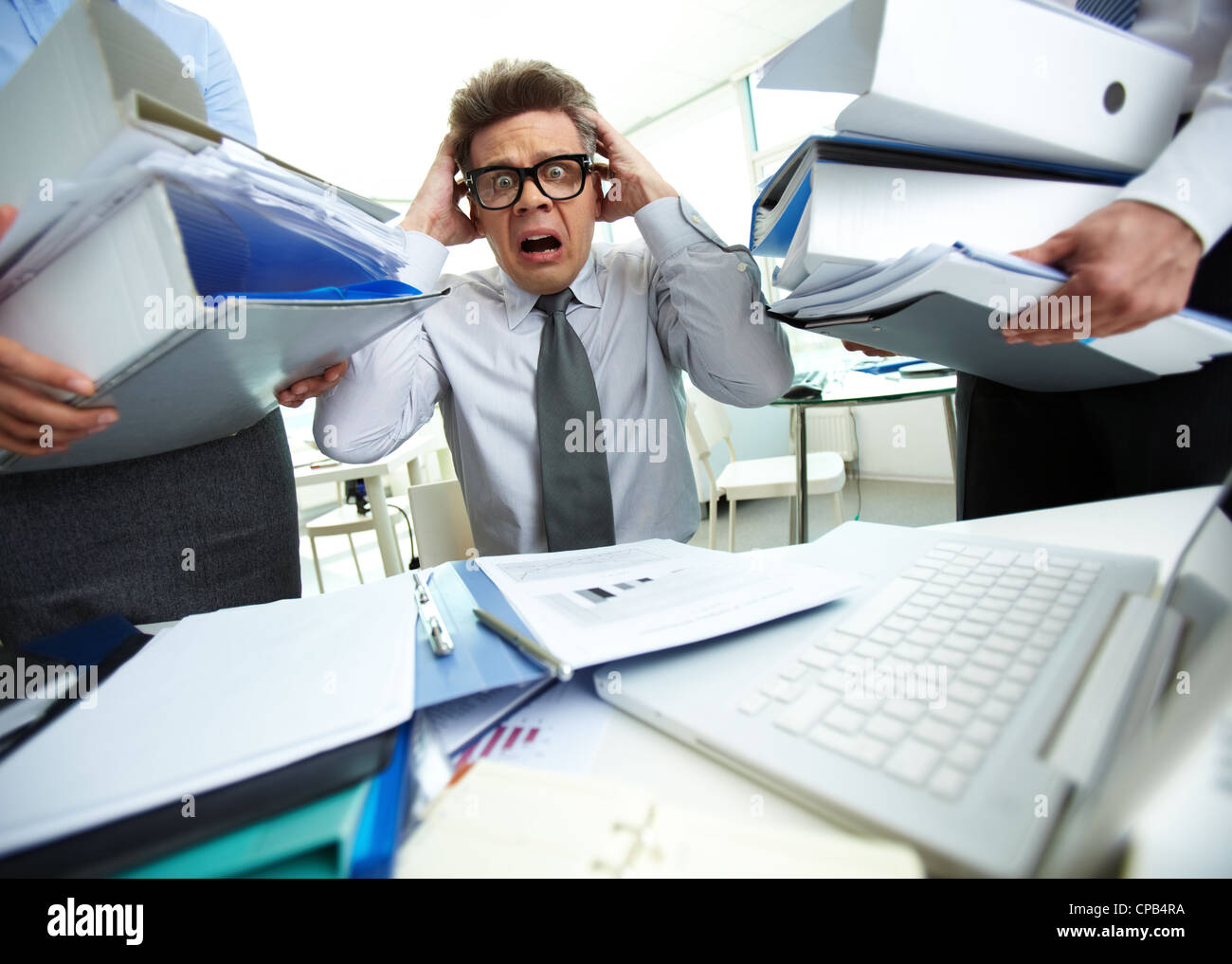 Terrified accountant touching his head being surrounded by huge piles ...