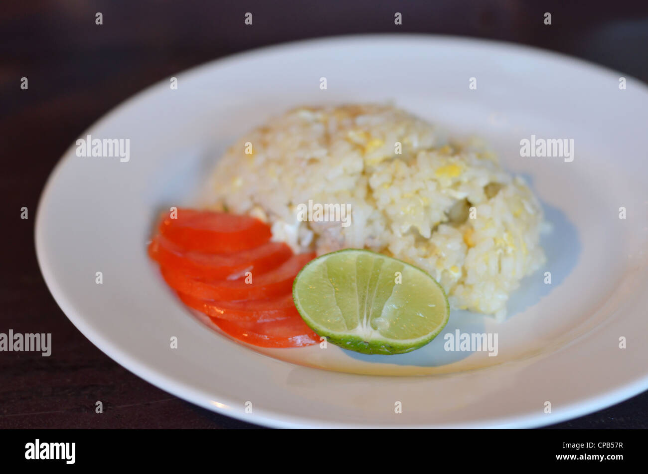 fried rice served with tomato and lemon Stock Photo - Alamy