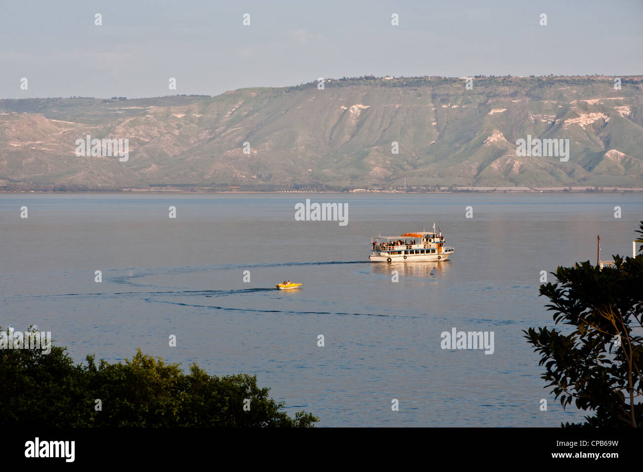 Tourist boats navigate the Sea of Galilee as the cliffs of the Golan ...