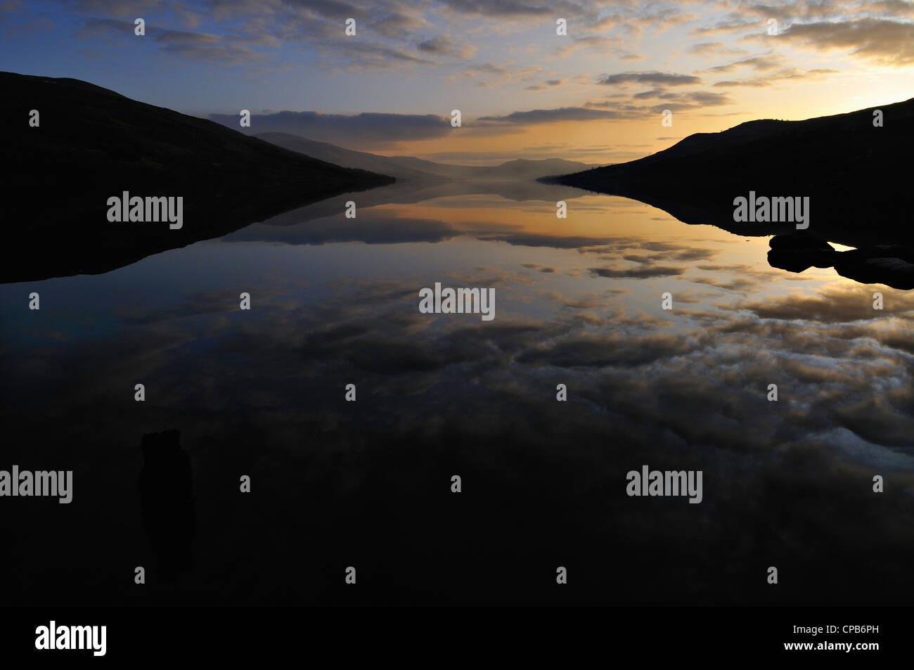 A sunset sky reflected in the still waters of Loch Tay, Perthshire ...