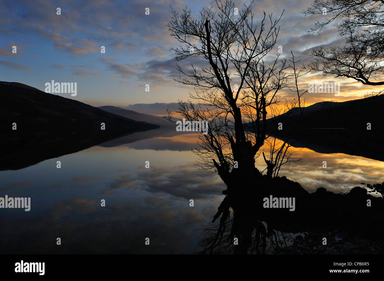 A sunset sky reflected in the still waters of Loch Tay, Perthshire ...