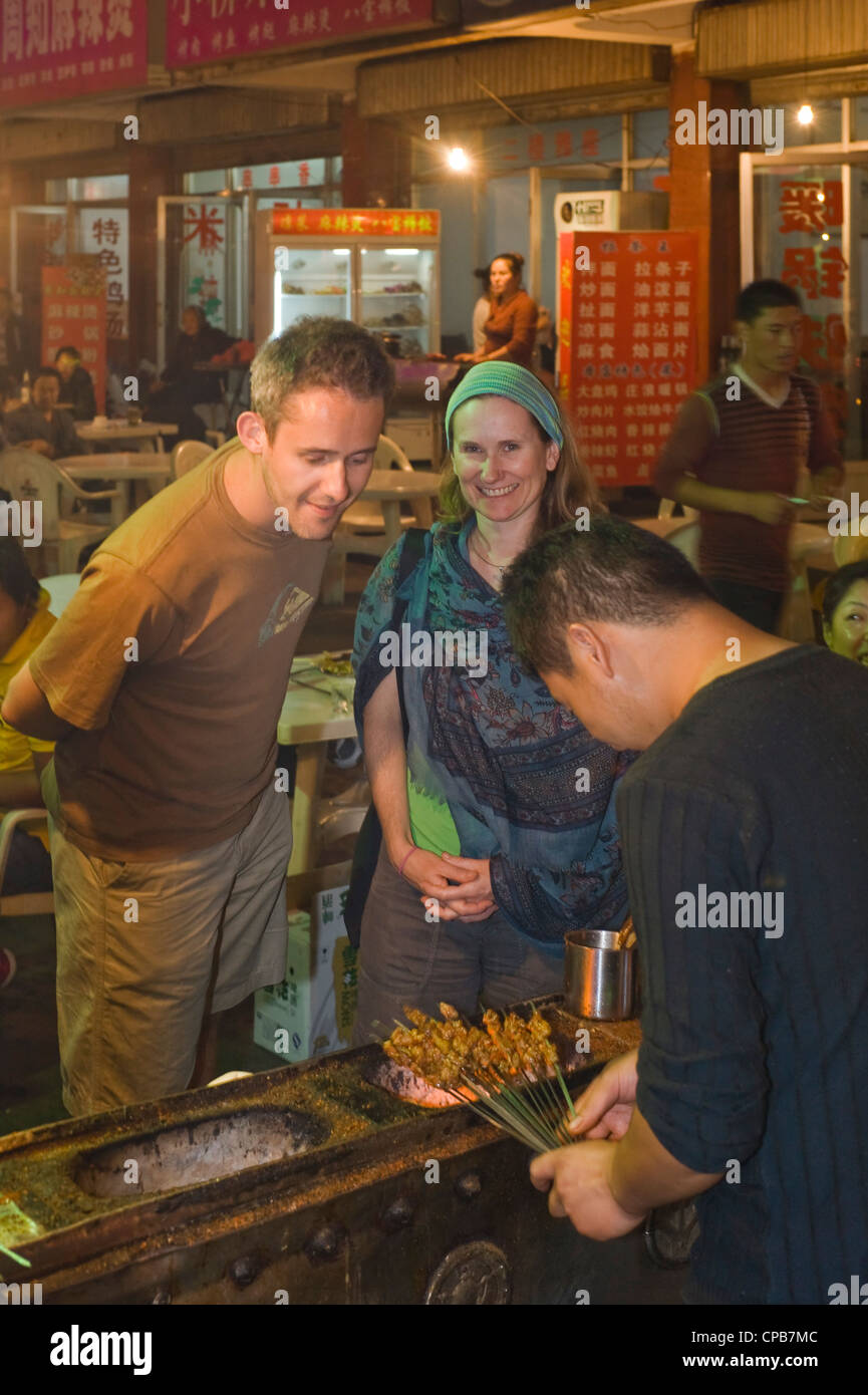 2 European tourists buy food from an outdoor street market vendor in ...