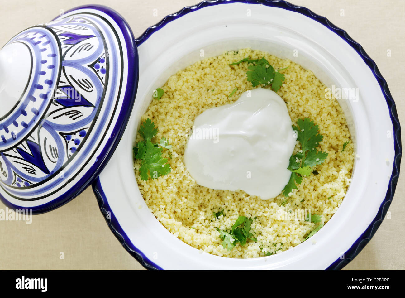 A north African pottery tagine bowl full of couscous, topped with fresh ...