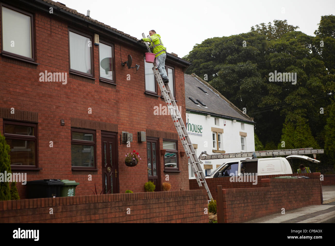 Man on ladder repairing roof Stock Photo - Alamy