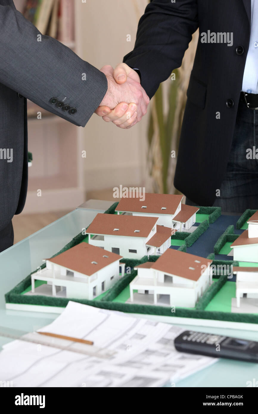 Handshake over a model housing estate Stock Photo - Alamy