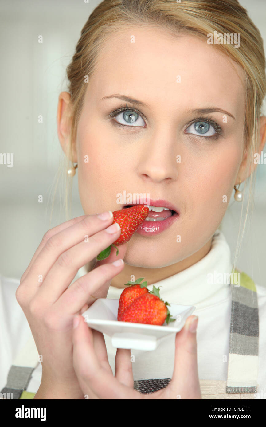 Blond woman eating strawberries Stock Photo - Alamy