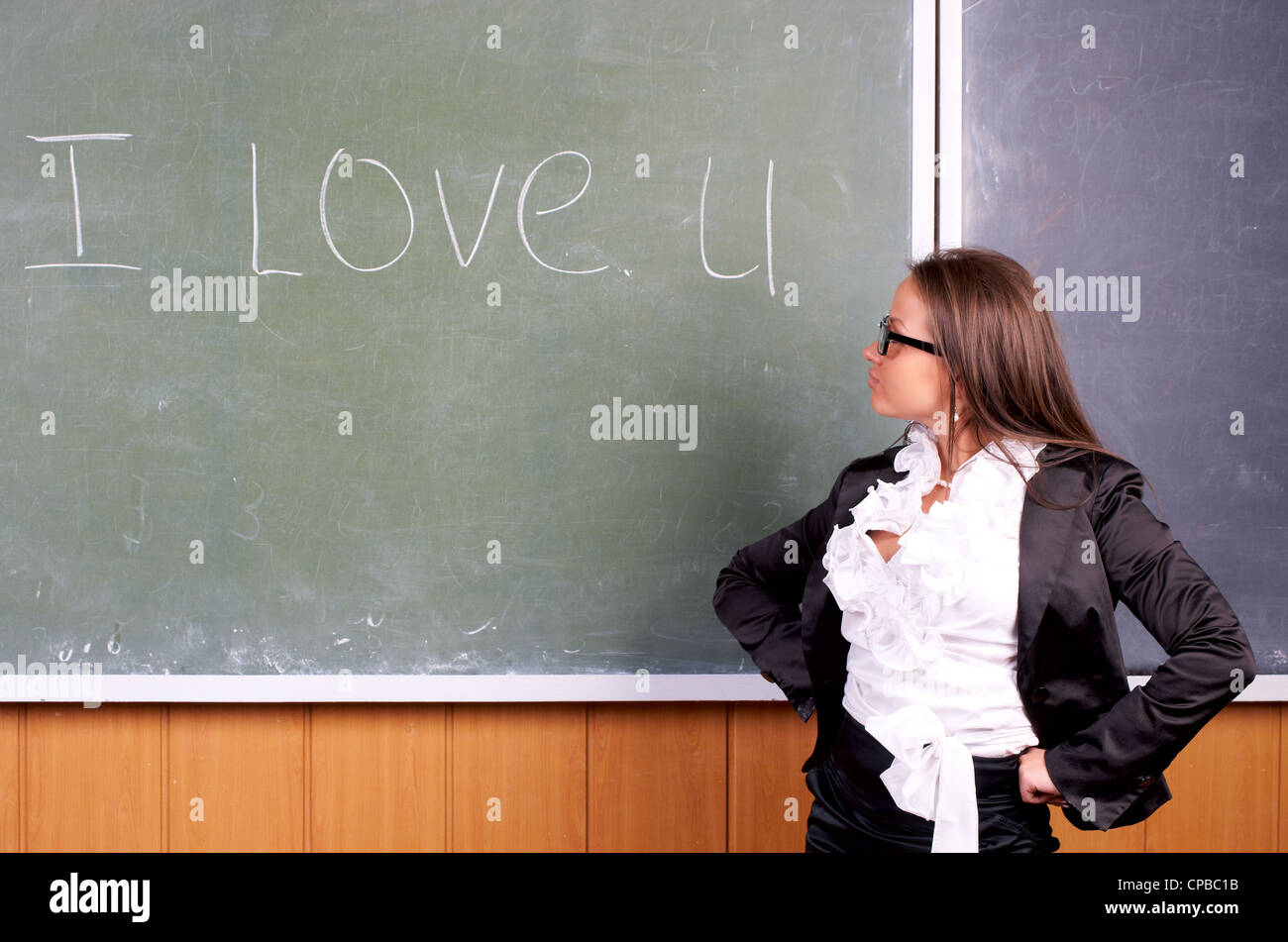 Beautiful young female teacher looking to the blackboard where "I love ...