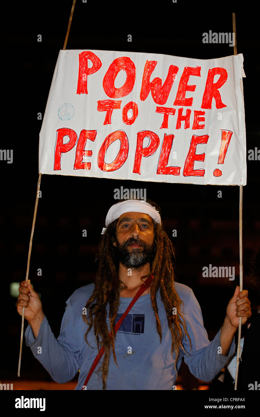 A demonstrator holds a paperboard sign which reads Power to the People ...