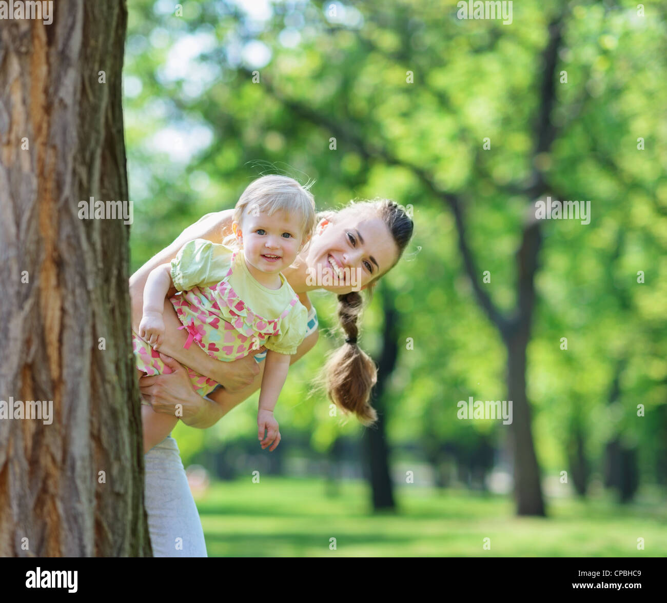 Happy mother and baby looking out from tree Stock Photo - Alamy