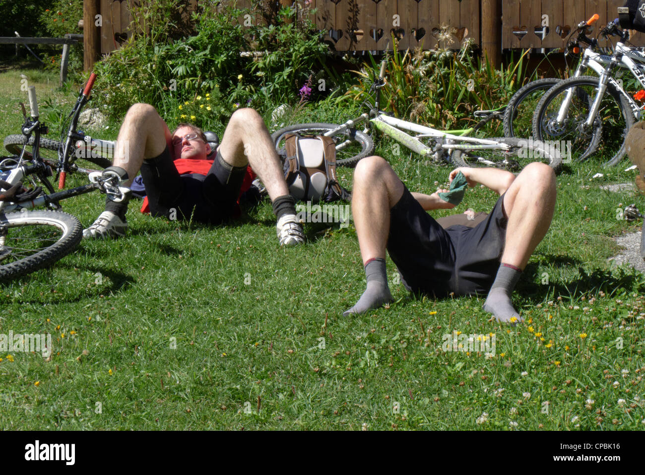 Tired cyclists relaxing on the grass on the mountain bike Tour de Mont ...