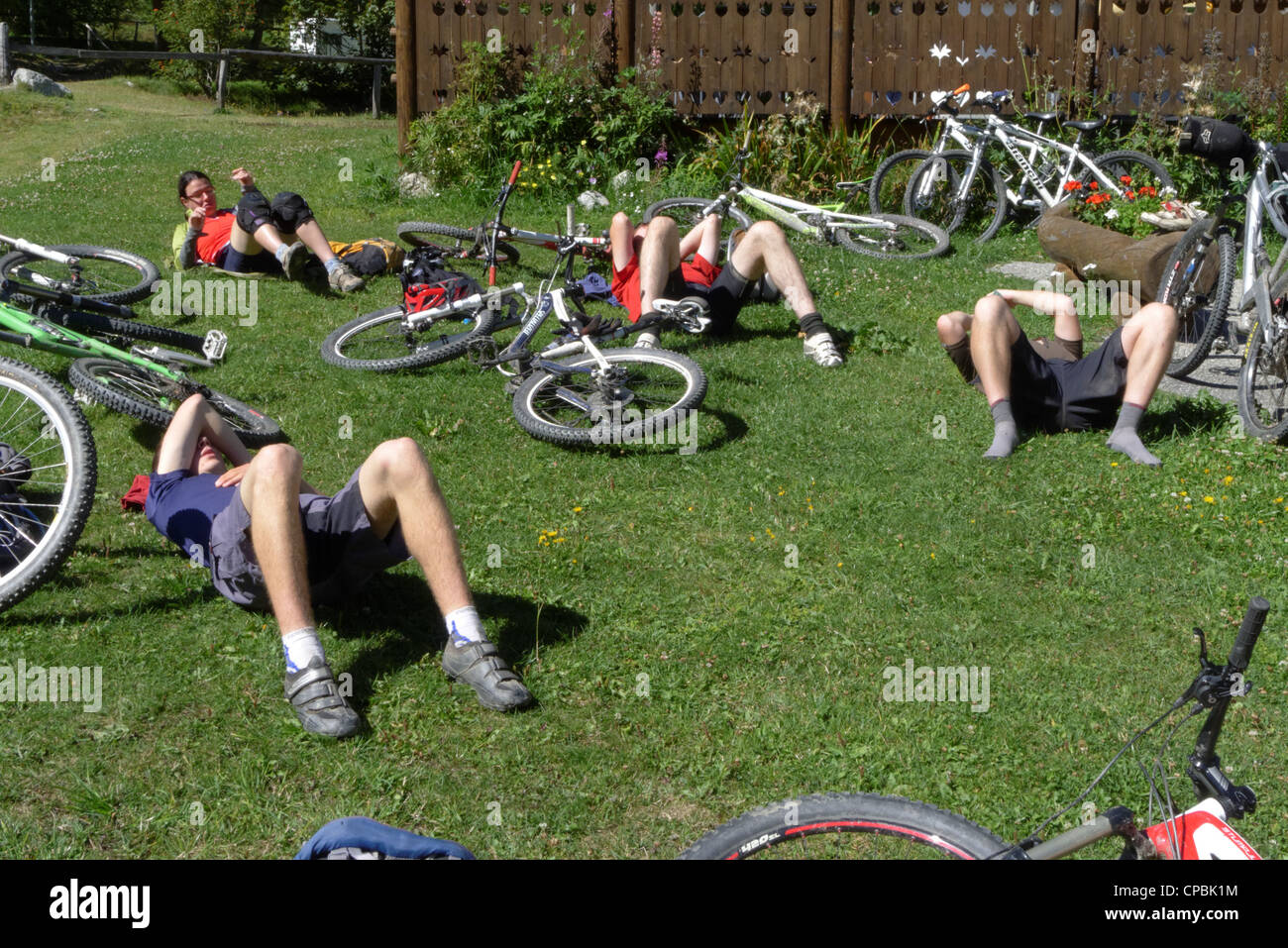 Tired cyclists relaxing on the grass on the mountain bike Tour de Mont ...