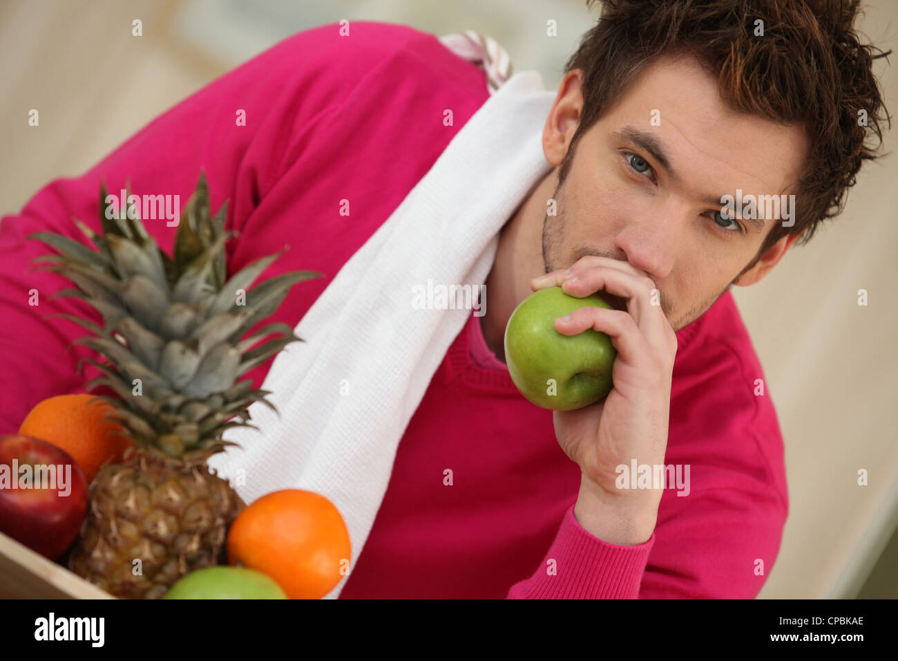 Pensive young man eating fruit Stock Photo - Alamy