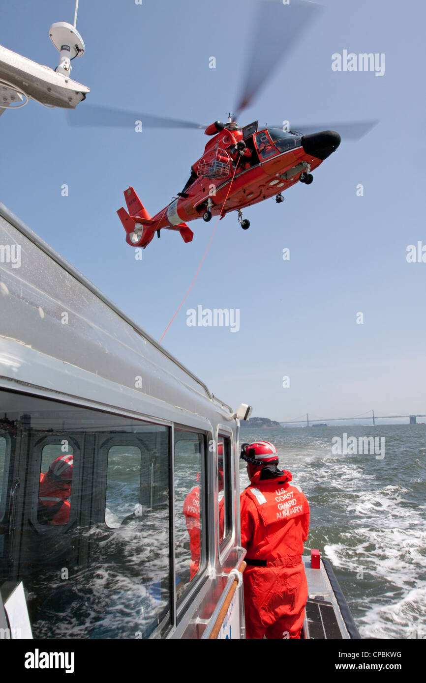 A United States Coast Guard HH-65C Dolphin helicopter lowers a rescue ...