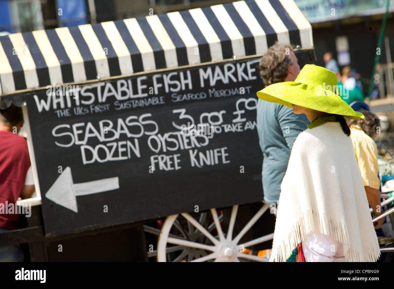 Woman in a large green hat at Whitstable Harbour fish market in Kent ...