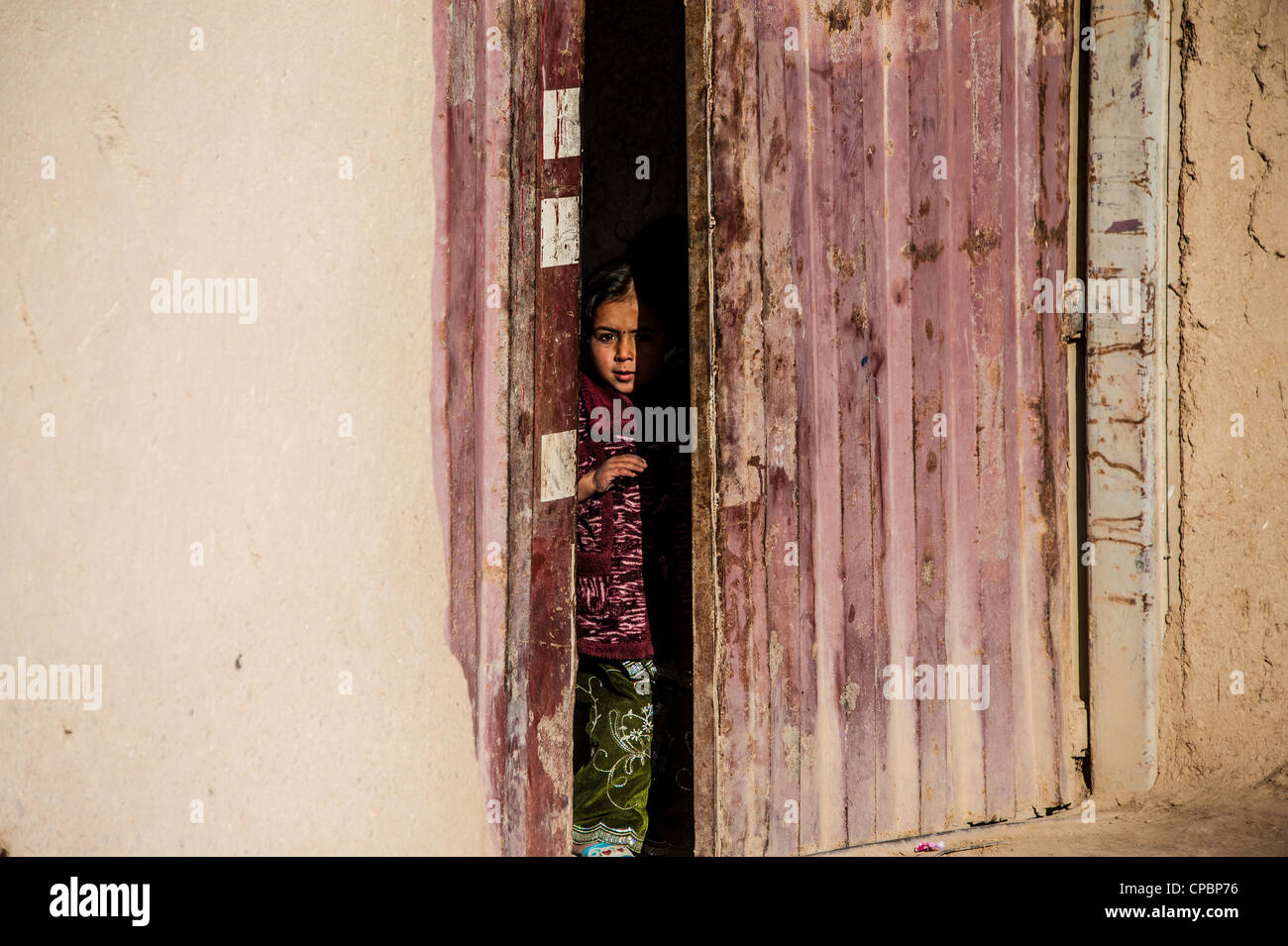 Afghan girl peeks from behind compound gate in Helmand Stock Photo - Alamy