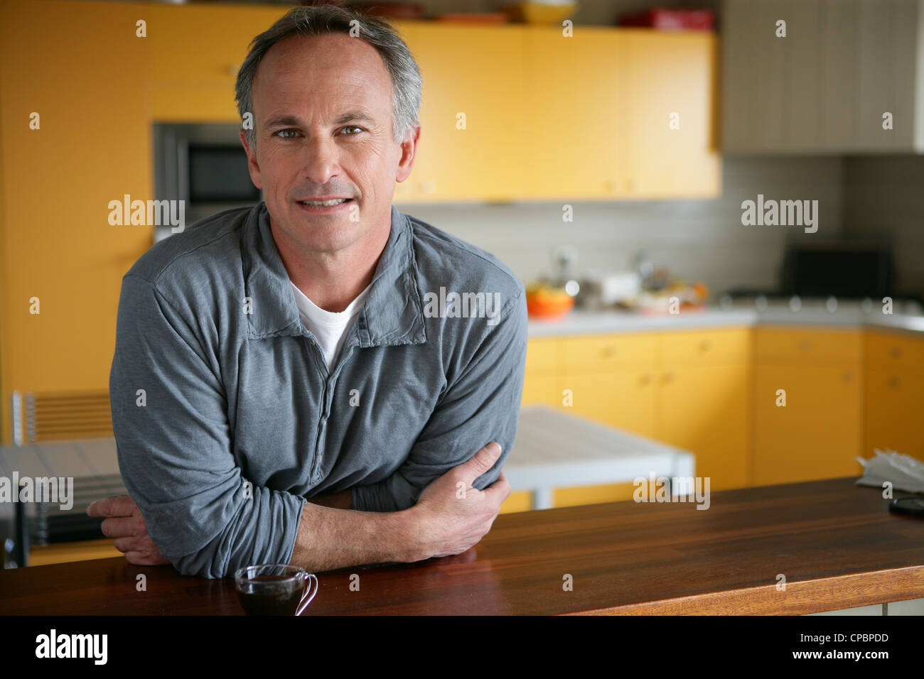 Man leaning on kitchen surface Stock Photo - Alamy