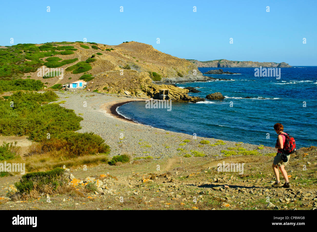 Walker above Caleta de Binallauti on the Cami de Cavalls coastal path ...