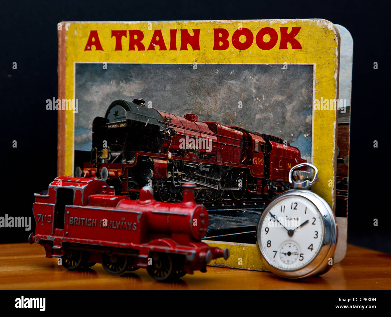 An old child's book about trains with a toy train and pocket watch in ...
