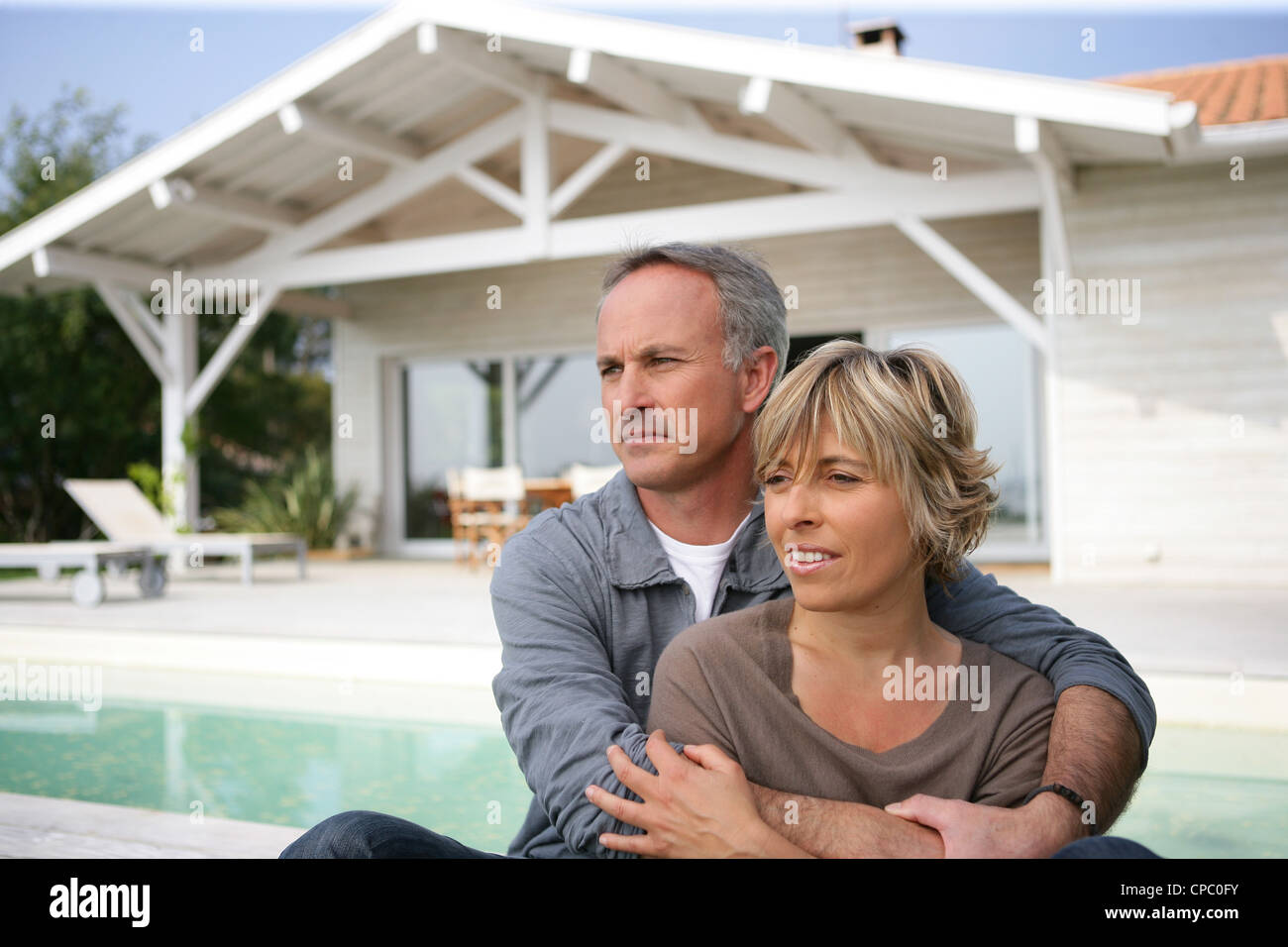 Couple sat in the garden by swimming pool Stock Photo - Alamy