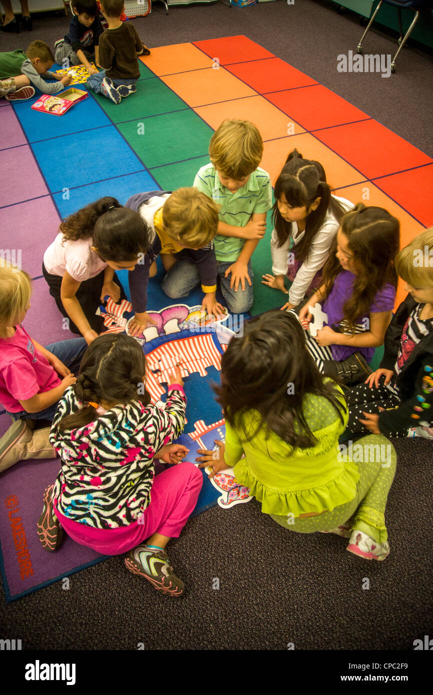 On a classroom floor, a group of kindergarten children collaborate to ...