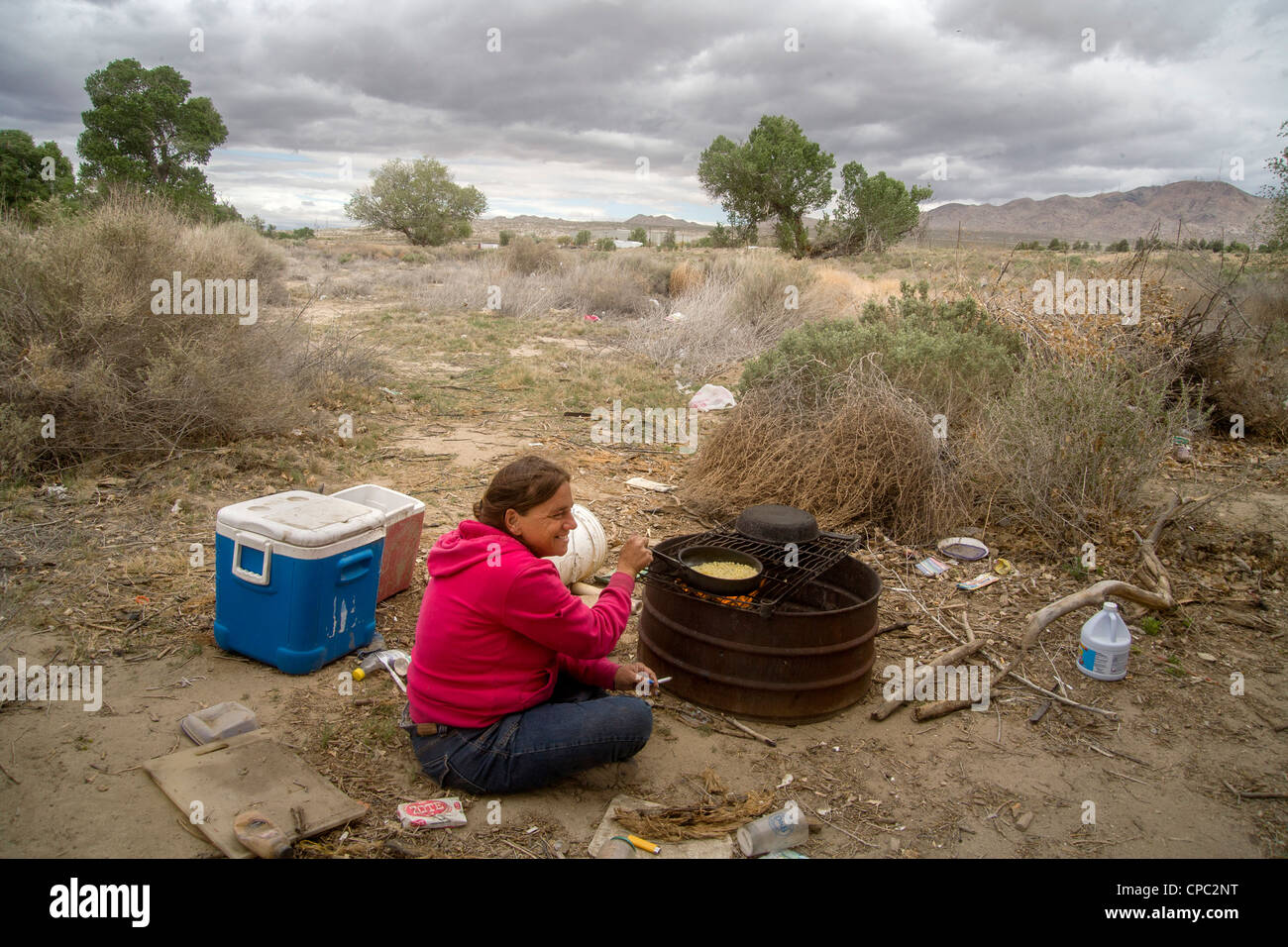 A homeless woman cooks corn on a primitive outdoor grill a primitive ...