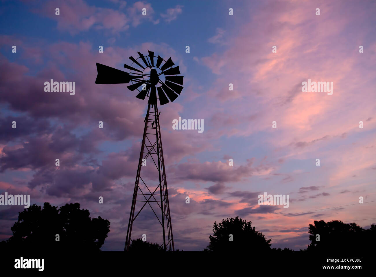 An old windmill in silhouette set against the setting sun Stock Photo ...