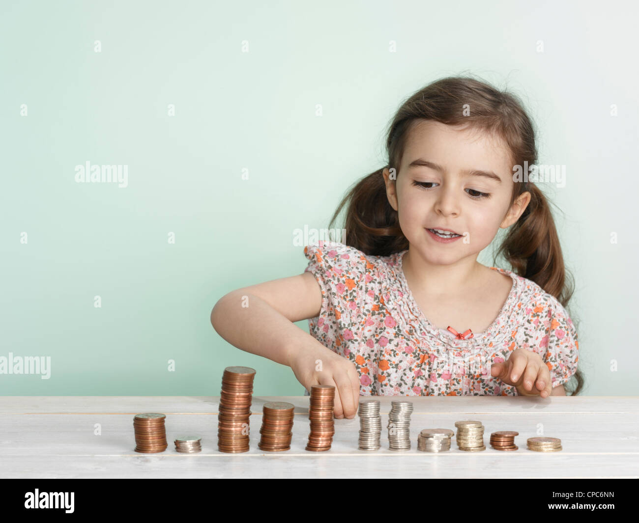 Girl stacking coins on counter Stock Photo - Alamy