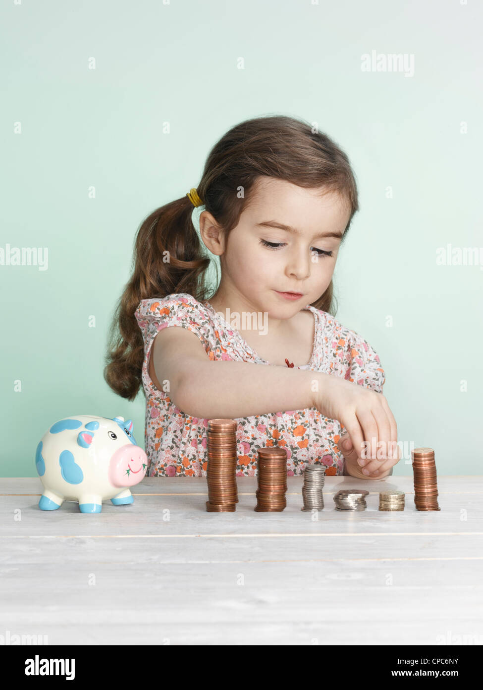 Girl stacking coins on counter Stock Photo - Alamy