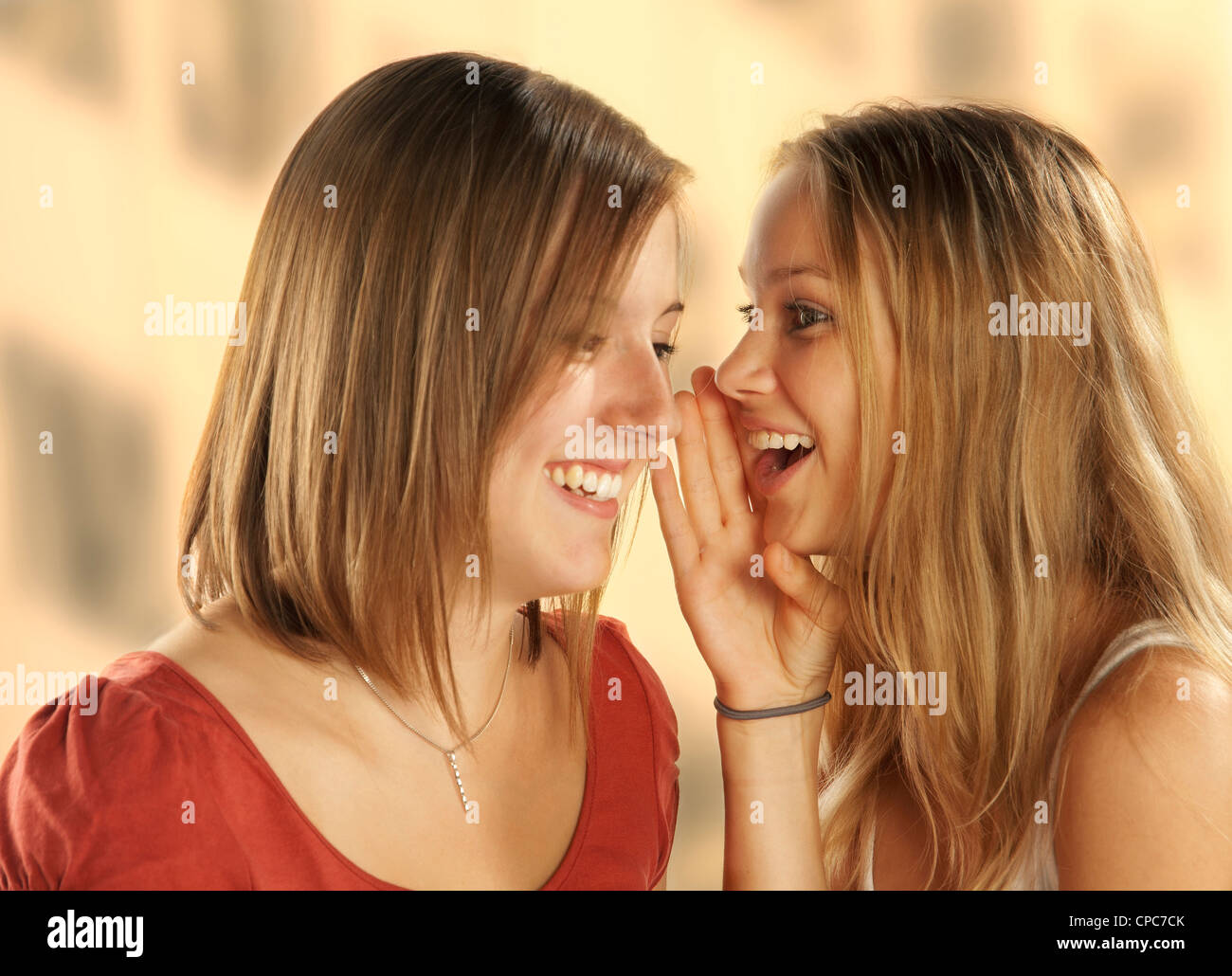 Young woman whispering in her friend's ear Stock Photo - Alamy