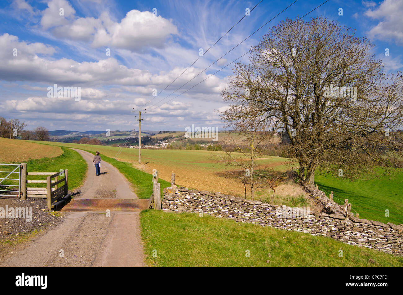 a woman walking down a country lane near Woodchester, Gloucestershire ...