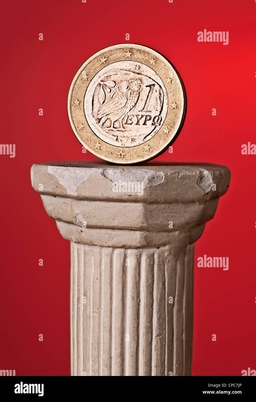 Greek € coin on a classical column in front of a red background. The ...
