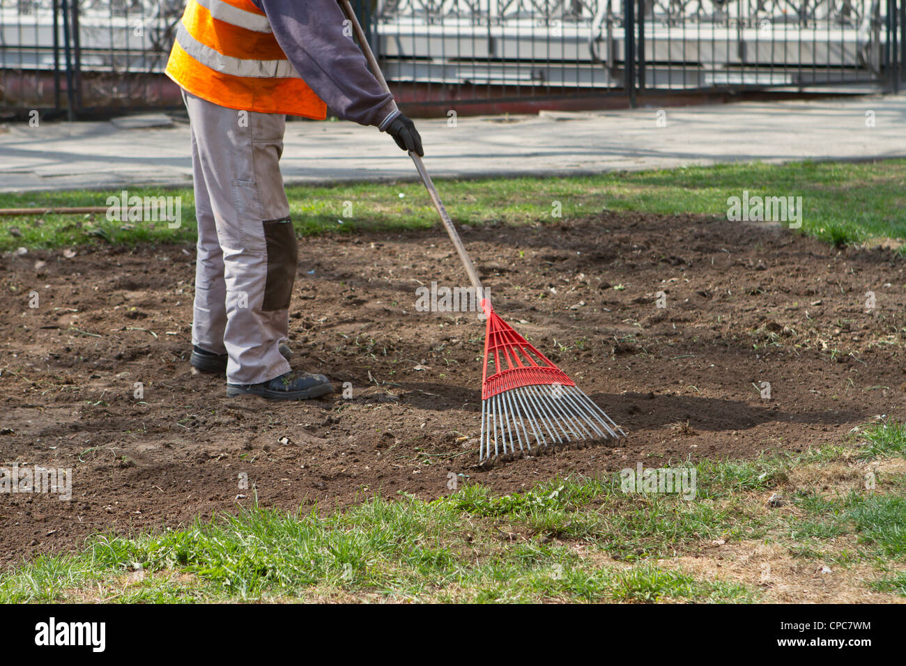 Gardener raking soil in a public park Stock Photo - Alamy