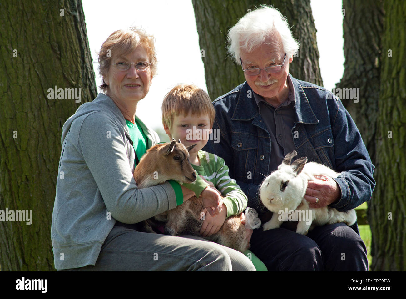 grandparents and grandson cuddling a rabbit and a goose Stock Photo - Alamy