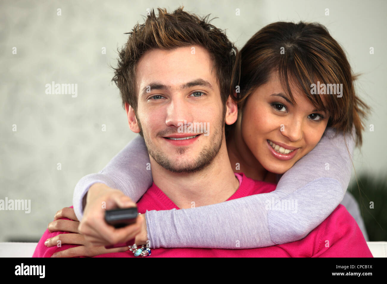 Young couple watching TV with a remote control Stock Photo - Alamy