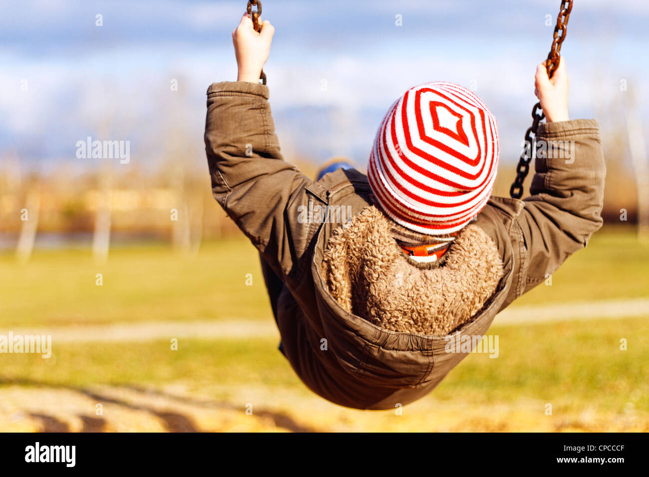 Boy (4-5) swinging at playground Stock Photo - Alamy