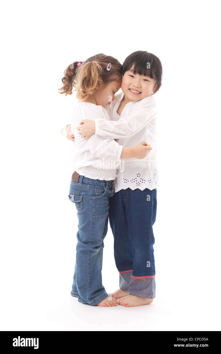 Two young girls hugging each other. Studio shot against a white ...