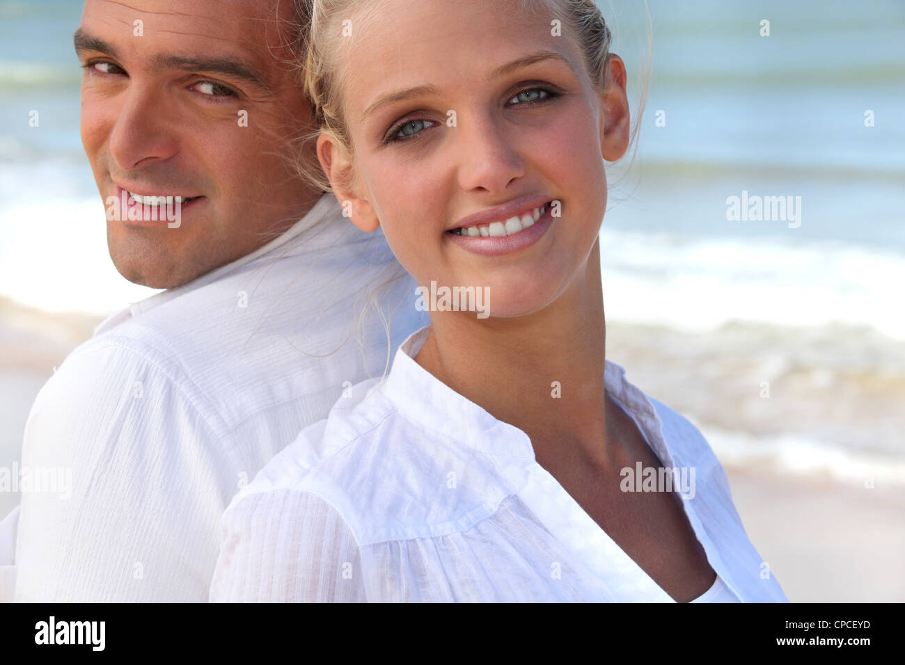 Couple back to back on the beach Stock Photo - Alamy