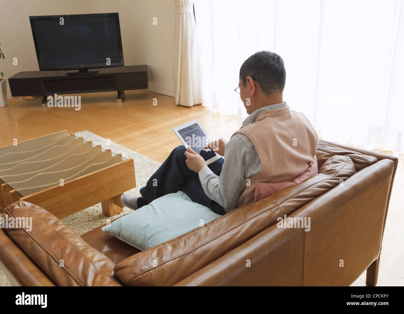 Senior man using tablet PC on a sofa Stock Photo - Alamy