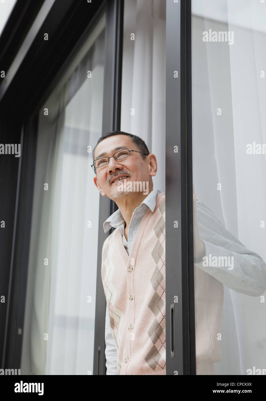 Senior man leaning out of window Stock Photo - Alamy
