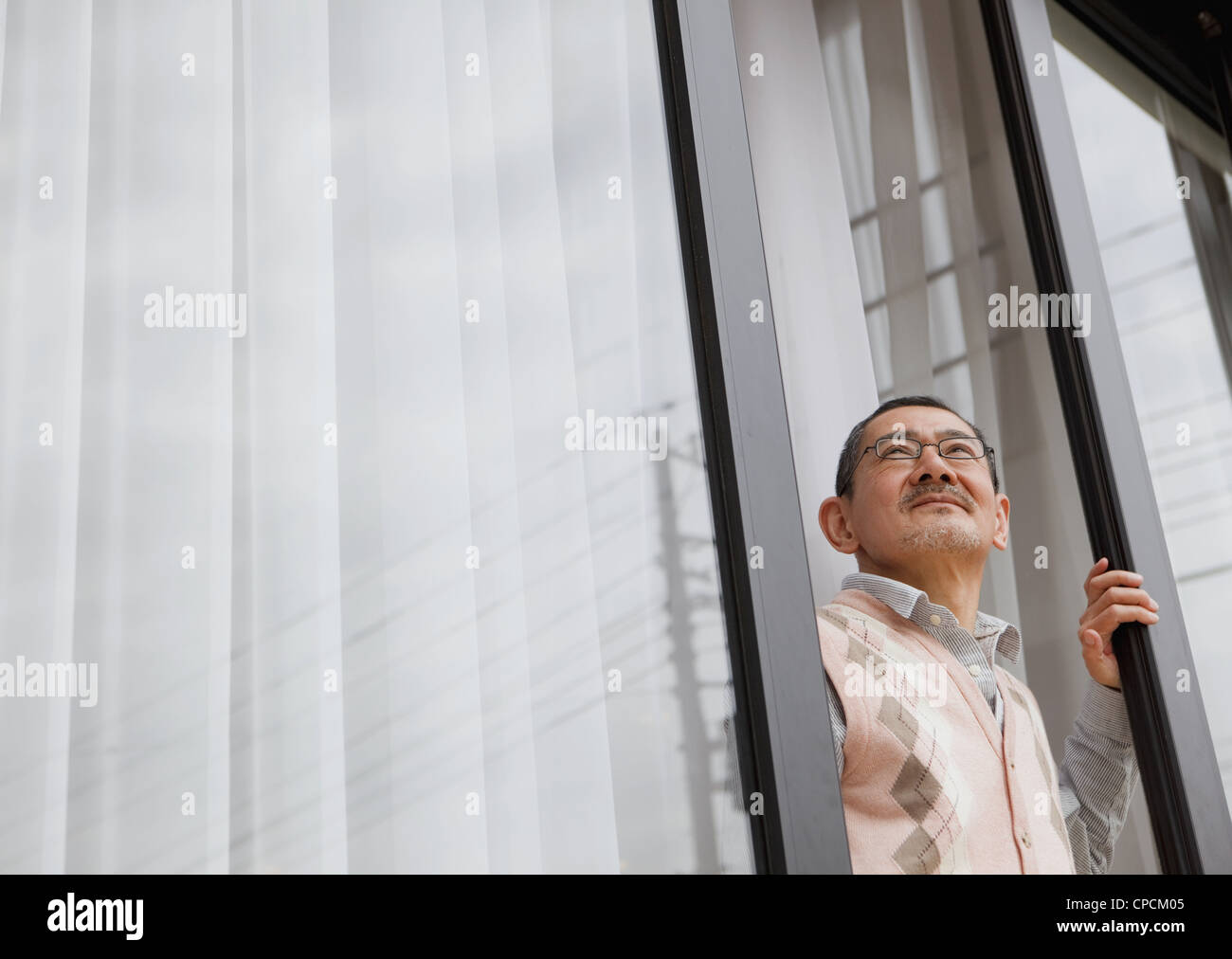 Senior man leaning out of window Stock Photo - Alamy