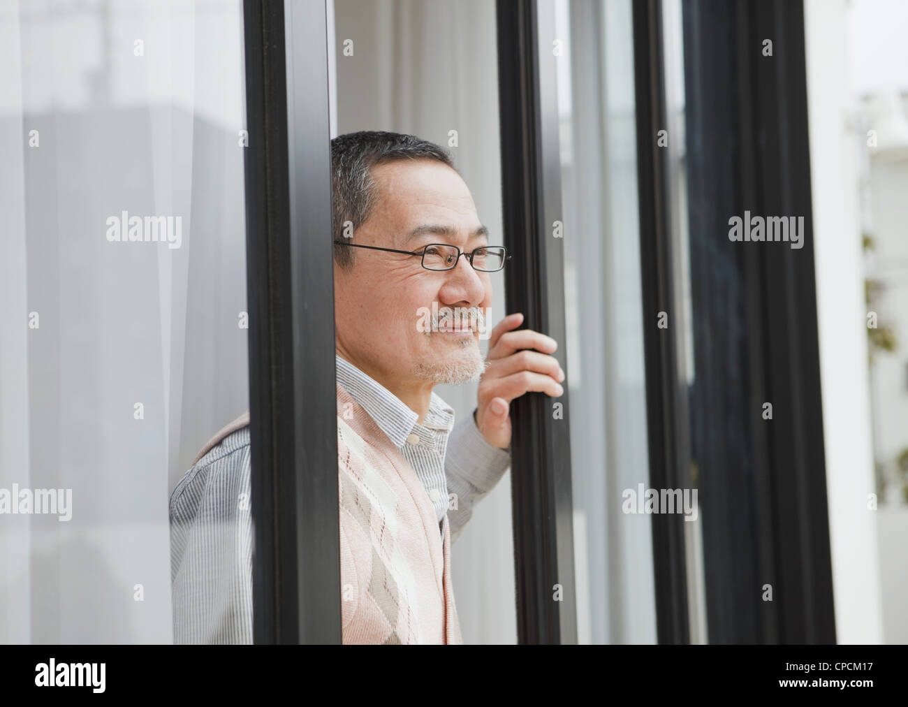Senior man leaning out of window Stock Photo - Alamy