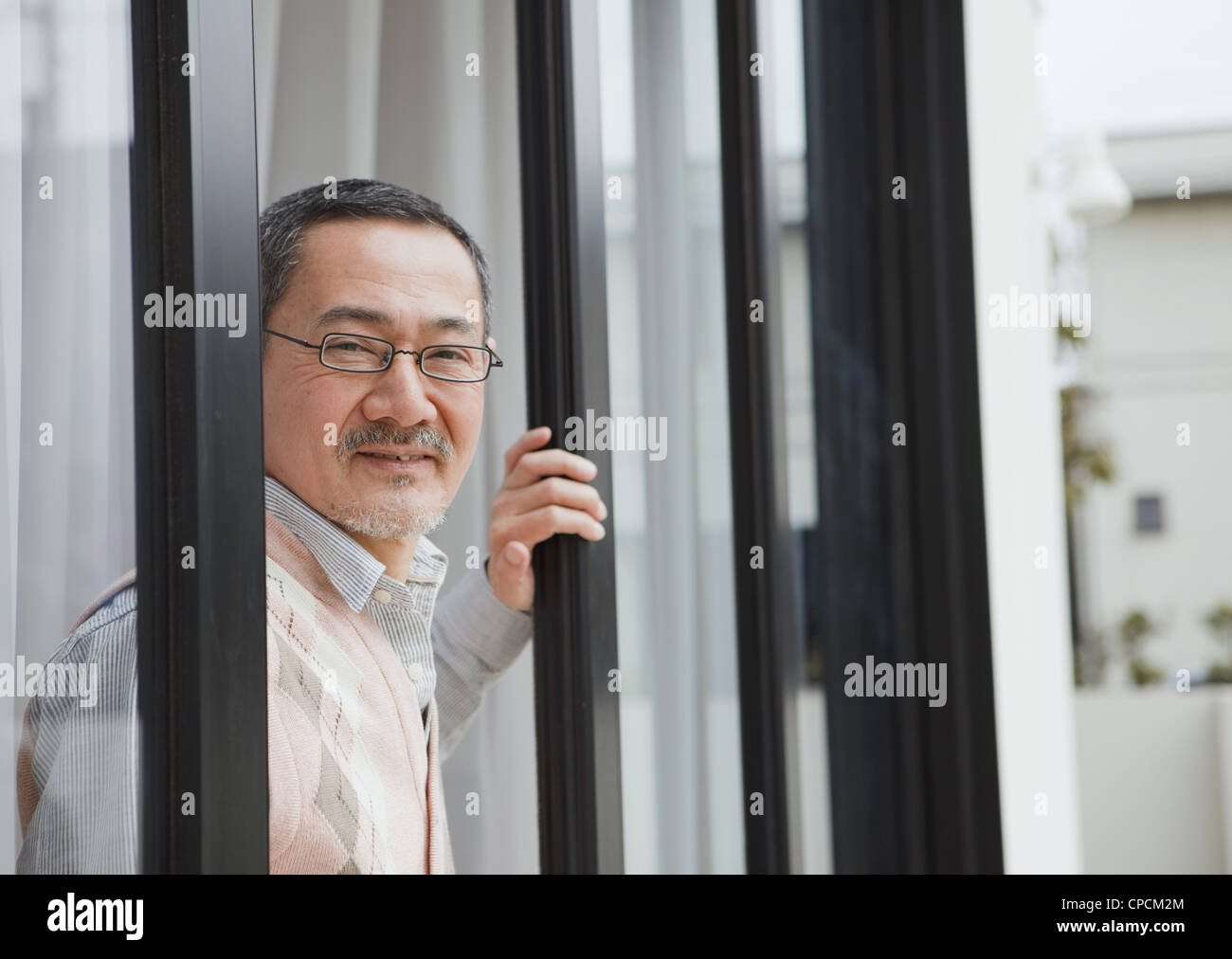 Senior man leaning out of window Stock Photo - Alamy