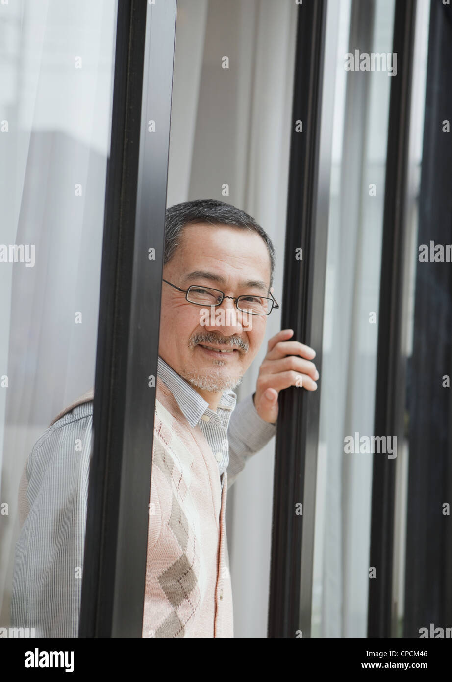 Senior man leaning out of window Stock Photo - Alamy