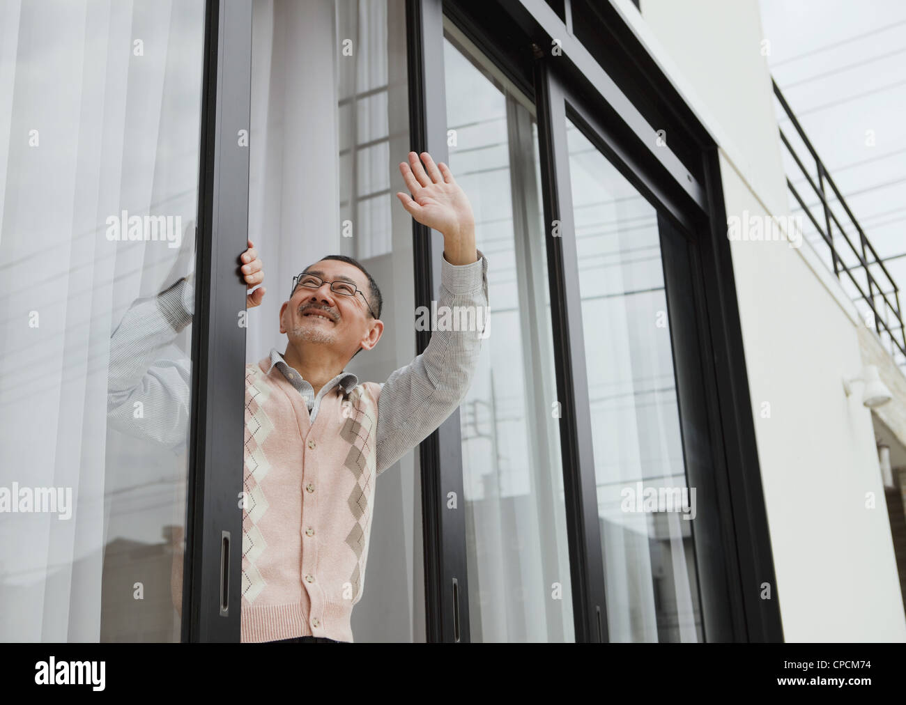 Senior man leaning out of window Stock Photo - Alamy